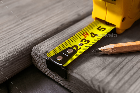 Carpenter is measuring length of wood planks or timbers by measuring ...