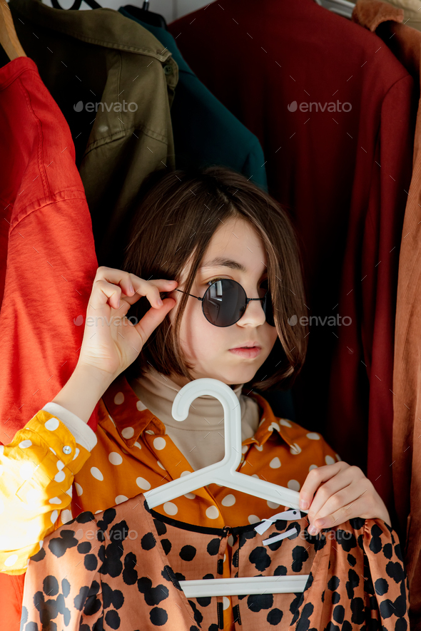 Stylish teenager girl is dressing up a clothes in wardrobe at home ...