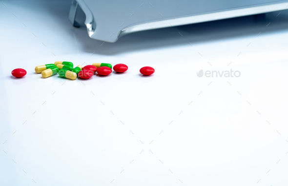 Red round sugar coated tablets and green yellow capsules with stainless ...