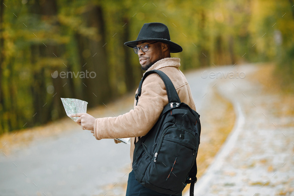 Black man standing on a road and looking at map Stock Photo by prostooleh