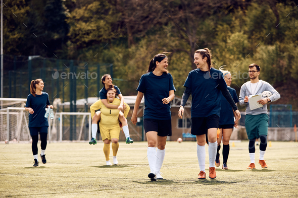Cheerful female players talking after soccer practice at the stadium ...