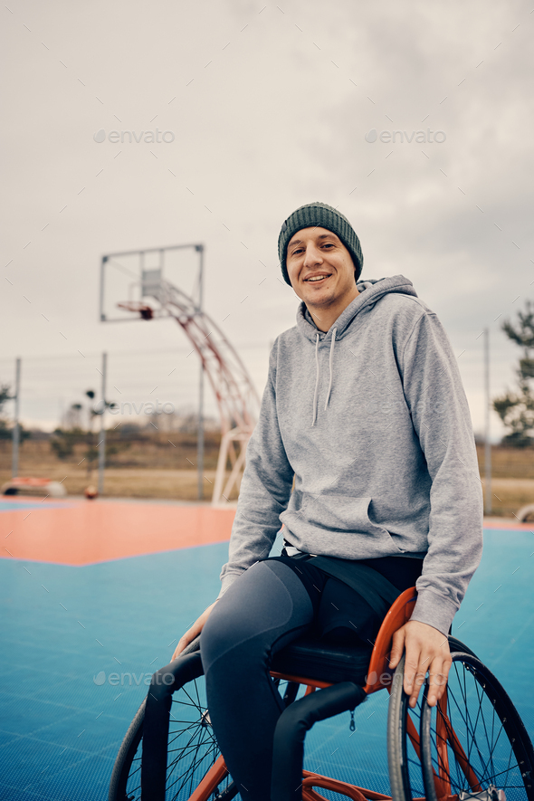 Portrait of happy amputee in wheelchair on outdoor basketball court ...