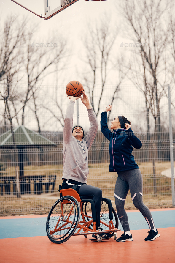 Athlete in wheelchair shooting at the hoop while playing basketball ...