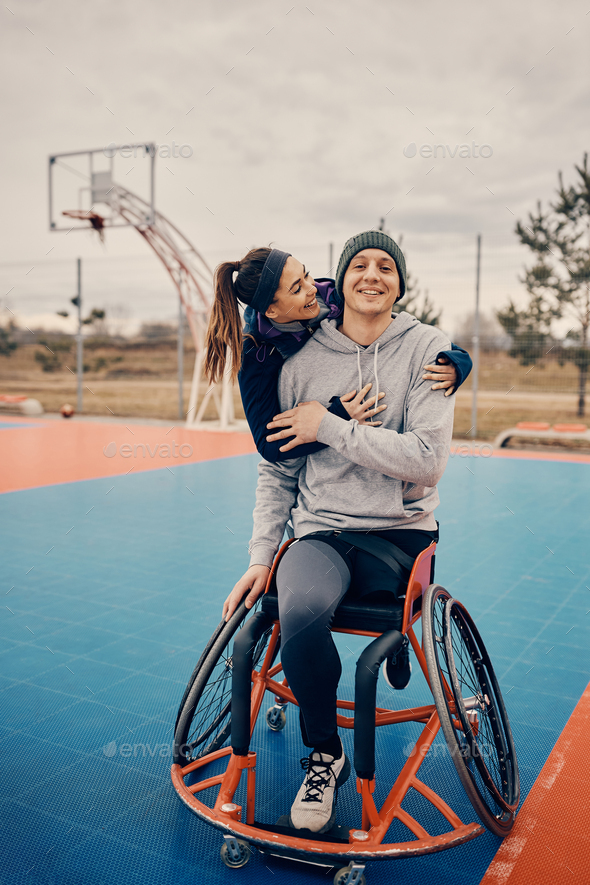 Happy disabled athlete and his girlfriend on an outdoor basketball ...