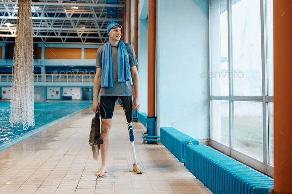 Full length of smiling swimmer with a prosthetic leg at indoors ...