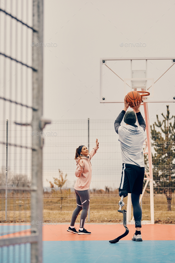 Rear view of athlete with artificial leg taking a shot while playing ...