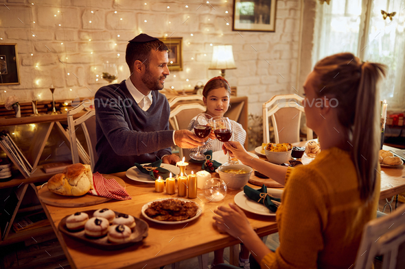 Happy Jewish family toasting during Hanukkah traditional dinner at ...