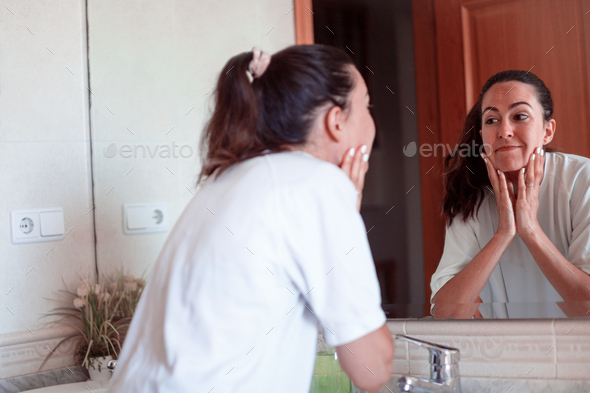 Rear view and face reflection portrait of young woman washing face in ...