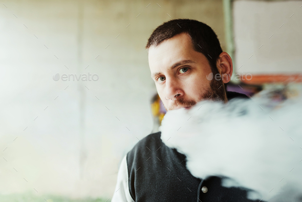 young man vaping his electronic cigarette Stock Photo by Meniphoto