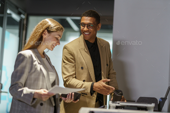 Two business people are talking while scanning documents on a scanner ...