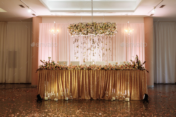 festive table for the bride and groom decorated with gold cloth, white and pink flowers and ...