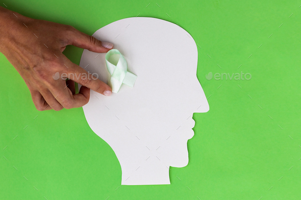 Brain paper cutout with green ribbon on green background with copy ...