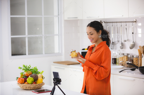 Cheerful young female chef and vlogger recording and going live on ...