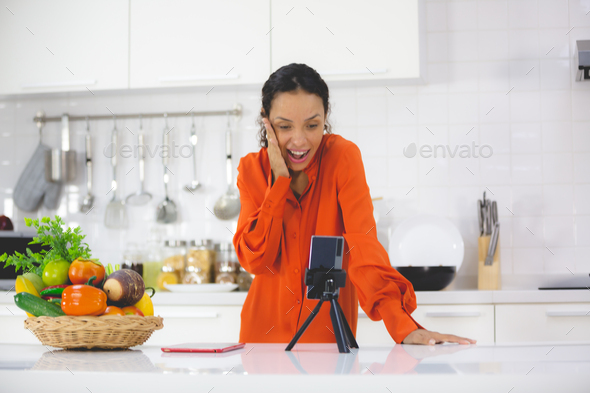 Cheerful young female chef and vlogger recording and going live on ...