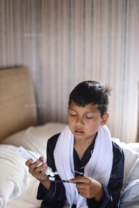 Sleepy Asian boy pouring toothpaste on toothbrush Stock Photo by ...