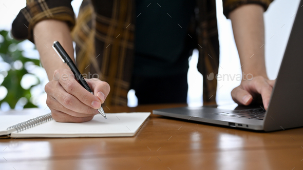 A professional male office worker in flannel shirt working at his desk ...