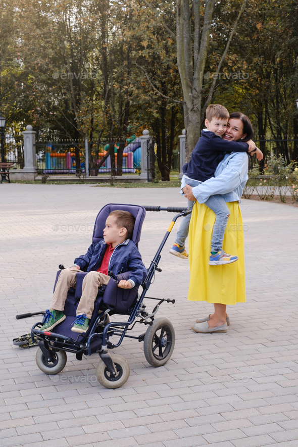 cerebral palsy child on medical stroller walking outdoors with mother ...