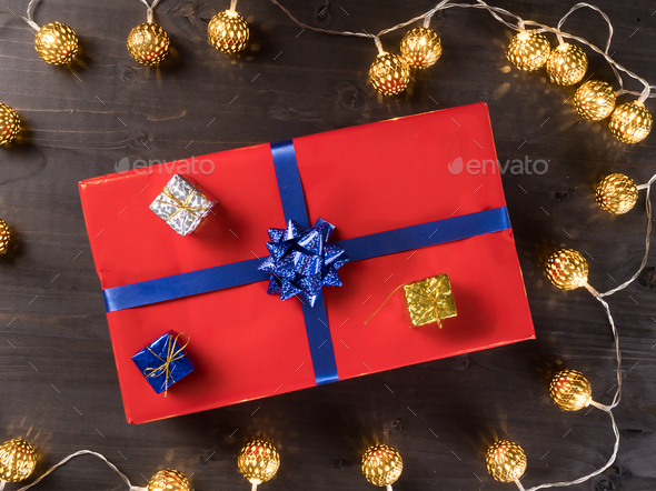 Red christmas gift box with smaller gift boxes on dark wooden floor ...