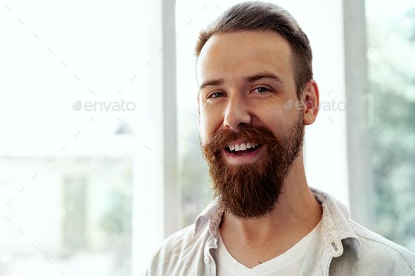 Bearded smiling handsome young man standing alone at home Stock Photo ...