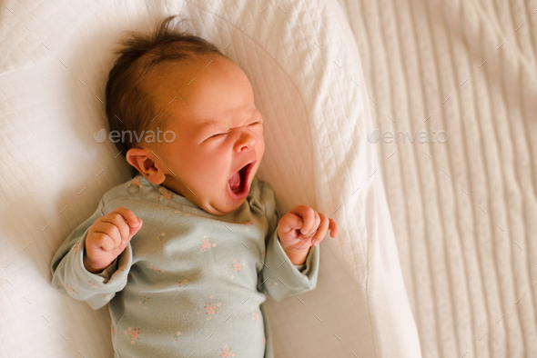 Yawning baby wake up in bed close up top view Stock Photo by morrowlight