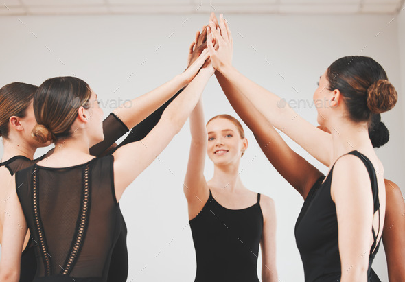 Shot of a group of ballet dancers joining their hands together in unity ...