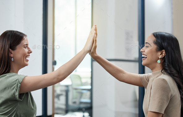 Shot of two businesswomen giving each other a high five in an office ...