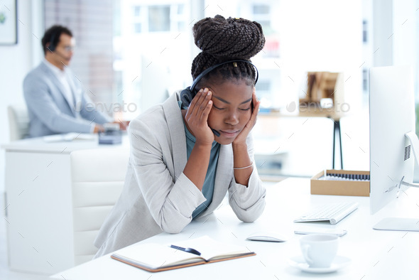Shot of a young call centre agent looking stressed out while working in ...