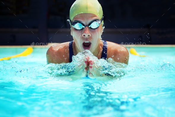Born to swim. Shot of a young female swimmer training by the pools ...