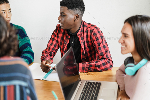 Multiracial students using laptop computers while studying together at ...