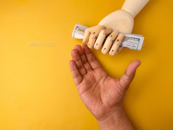 Someone’s hand was asking for money to a wooden hand that was holding a ...