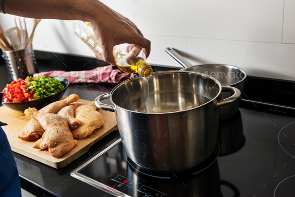 Chef hand pouring oil into a cooking pot Stock Photo by Raul_Mellado