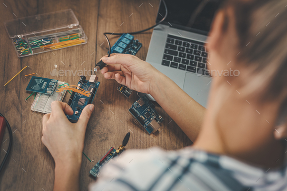 Female Engineer Testing Circuit Board In Her Office Stock Photo by micens