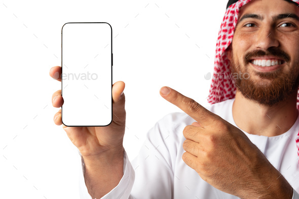 Young Arab muslim man in traditional clothes showing mobile phone ...