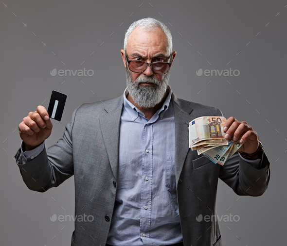 Rich old man with money and bank card against gray background Stock ...
