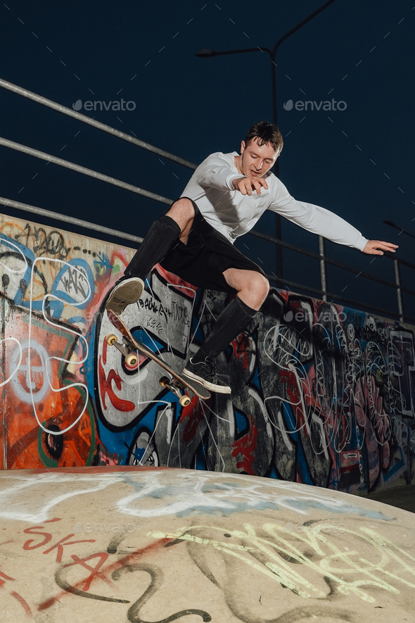 Skilled guy skateboarding at skate park at night time Stock Photo by ...