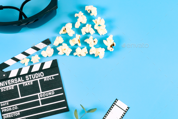 Paper cinema clapperboard, glasses, popcorn and film strip on a blue ...