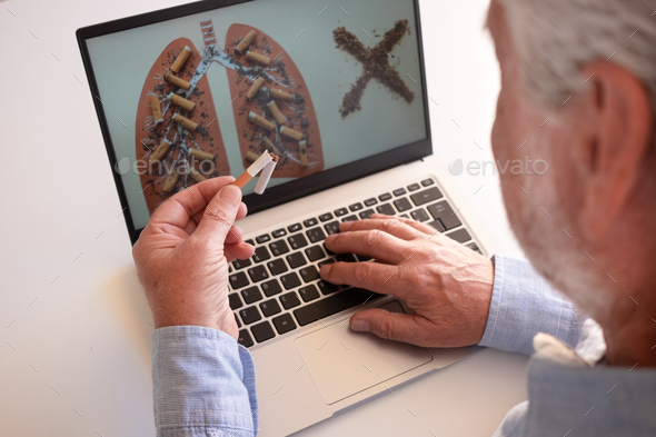 Adult man hand holding a broken cigarette over laptop keyboard, ready ...