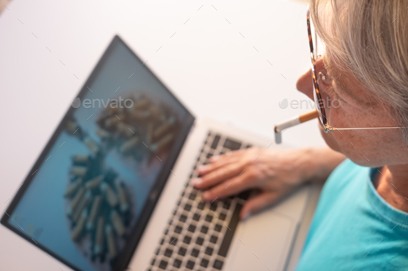 Close-up on female face with a cigarette in her mouth while typing on ...