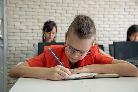 high school student wearing glasses reading a book or doing homework in ...