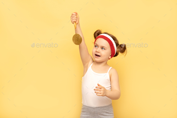 smiling happy athlete champion child girl celebrates gold medal. Sport ...