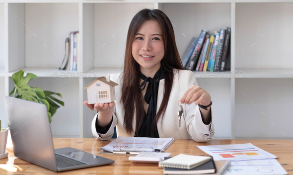 Miniature house in the hands of an Asian woman real estate agent home ...