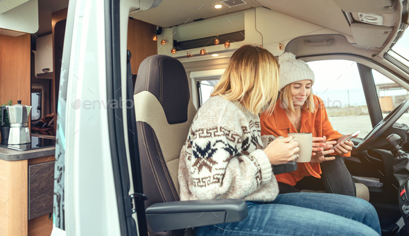 Women with a coffee looking mobile sitting in the front seat of a ...