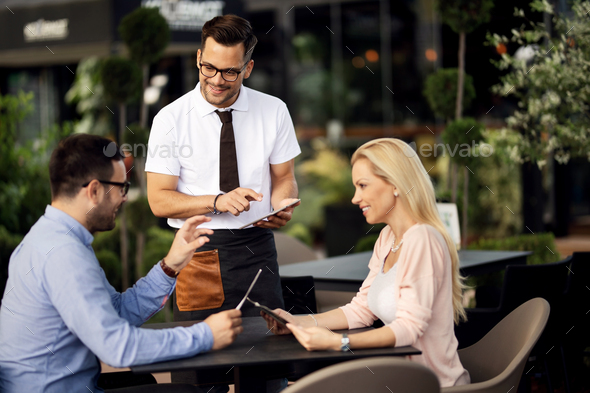 Smiling waiter taking order from a couple in an outdoor cafe, Stock ...