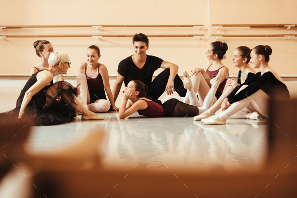 Ballet teacher talking with her students while relaxing on the floor at ...