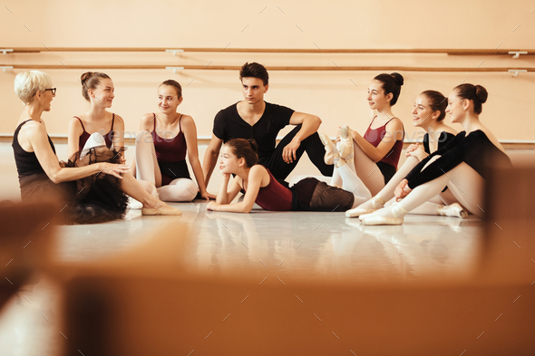 Large group of ballet dancers and their teacher talk while relaxing ...