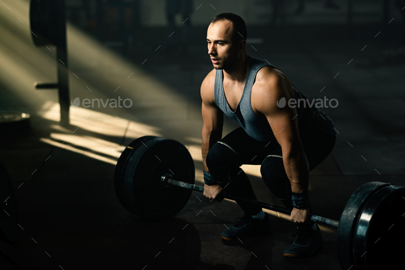 Muscular build man performing deadlift while having weight training in ...
