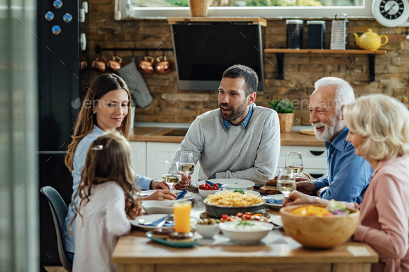 Happy extended family talking while having lunch at dining table. Stock ...