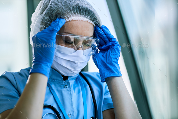 Overworked healthcare worker holding her head in pain at medical clinic ...
