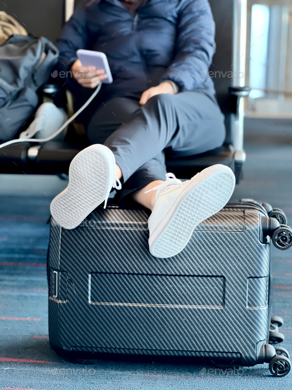 Selective focus of female with feet on suitcase while using mobile ...