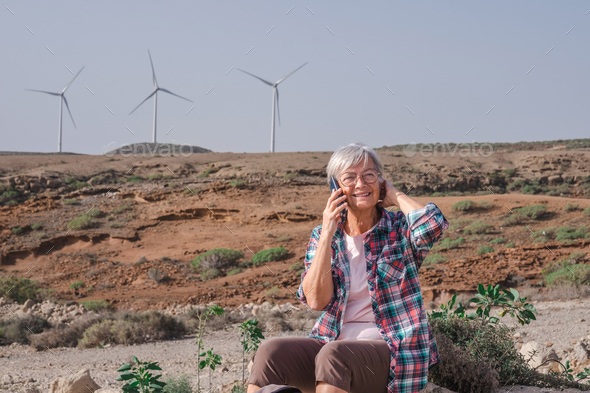 Alternative energy, wind farm. Senior woman sitting in wind turbines ...